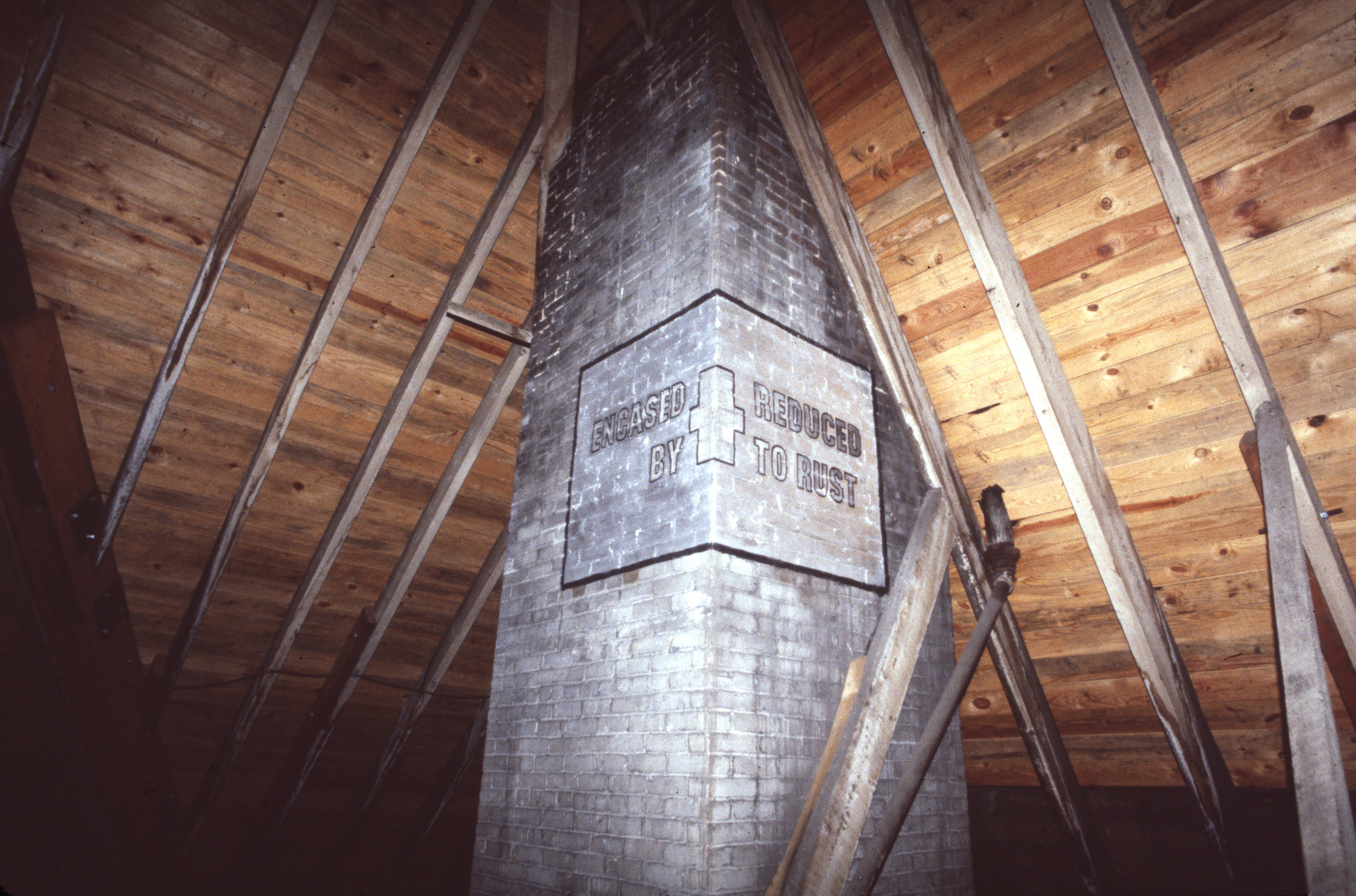 Installation view of Lawrence Weiner's work, "Encased By + Reduced to ...